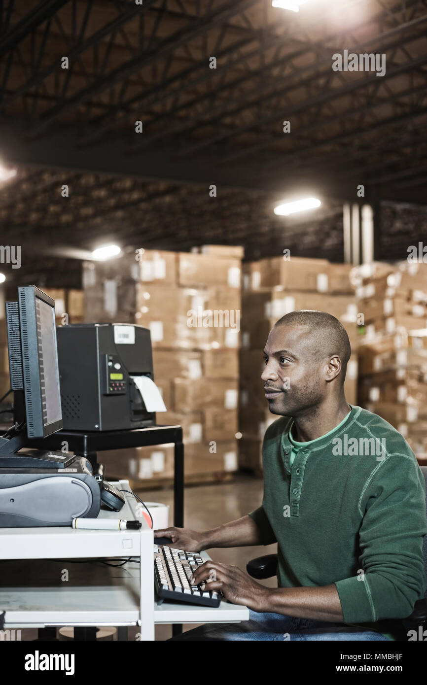 African American male warehouse worker working on a desktop computer in ...