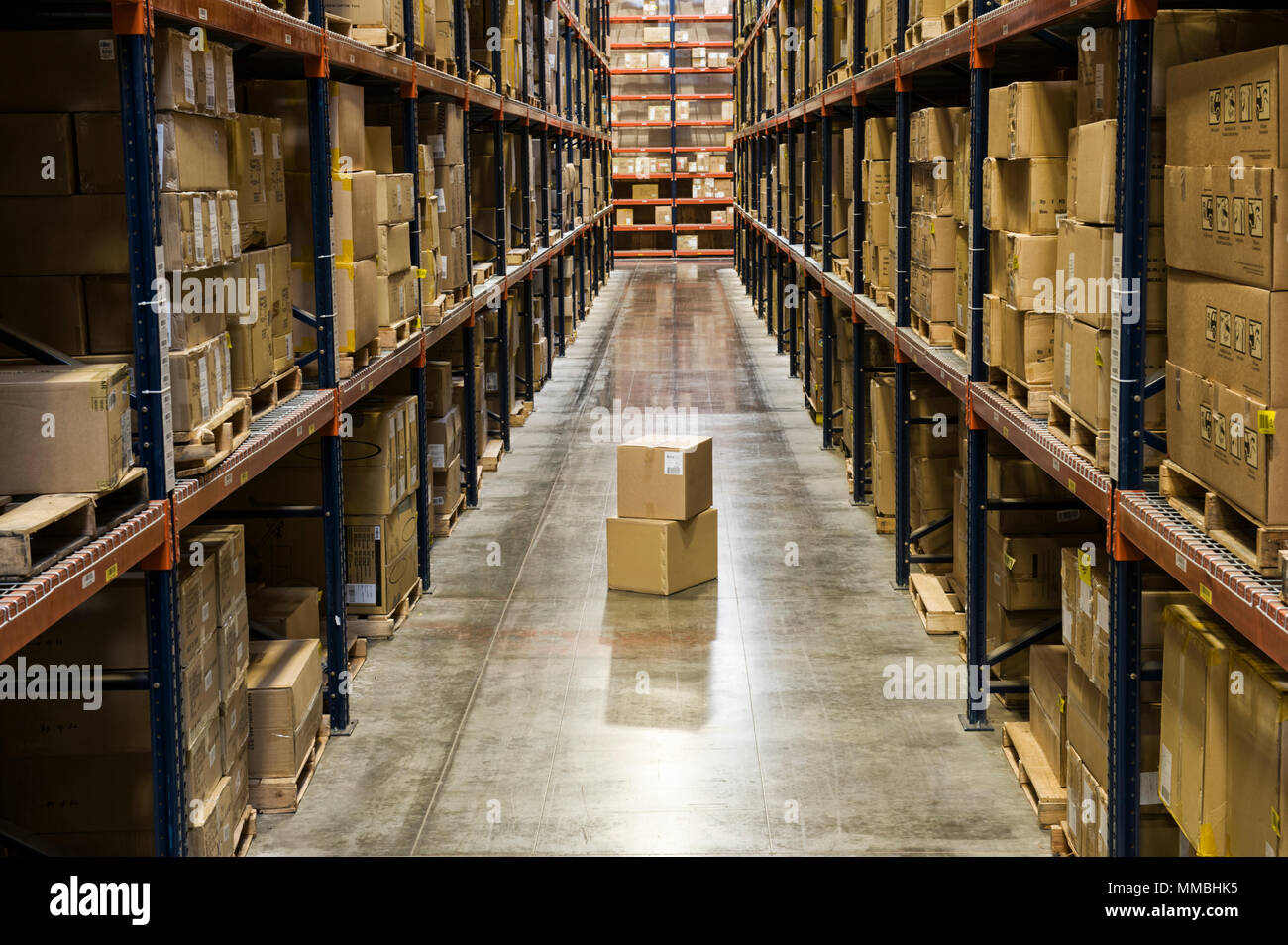 View down an aisle of racks holding cardboard boxes of product on ...