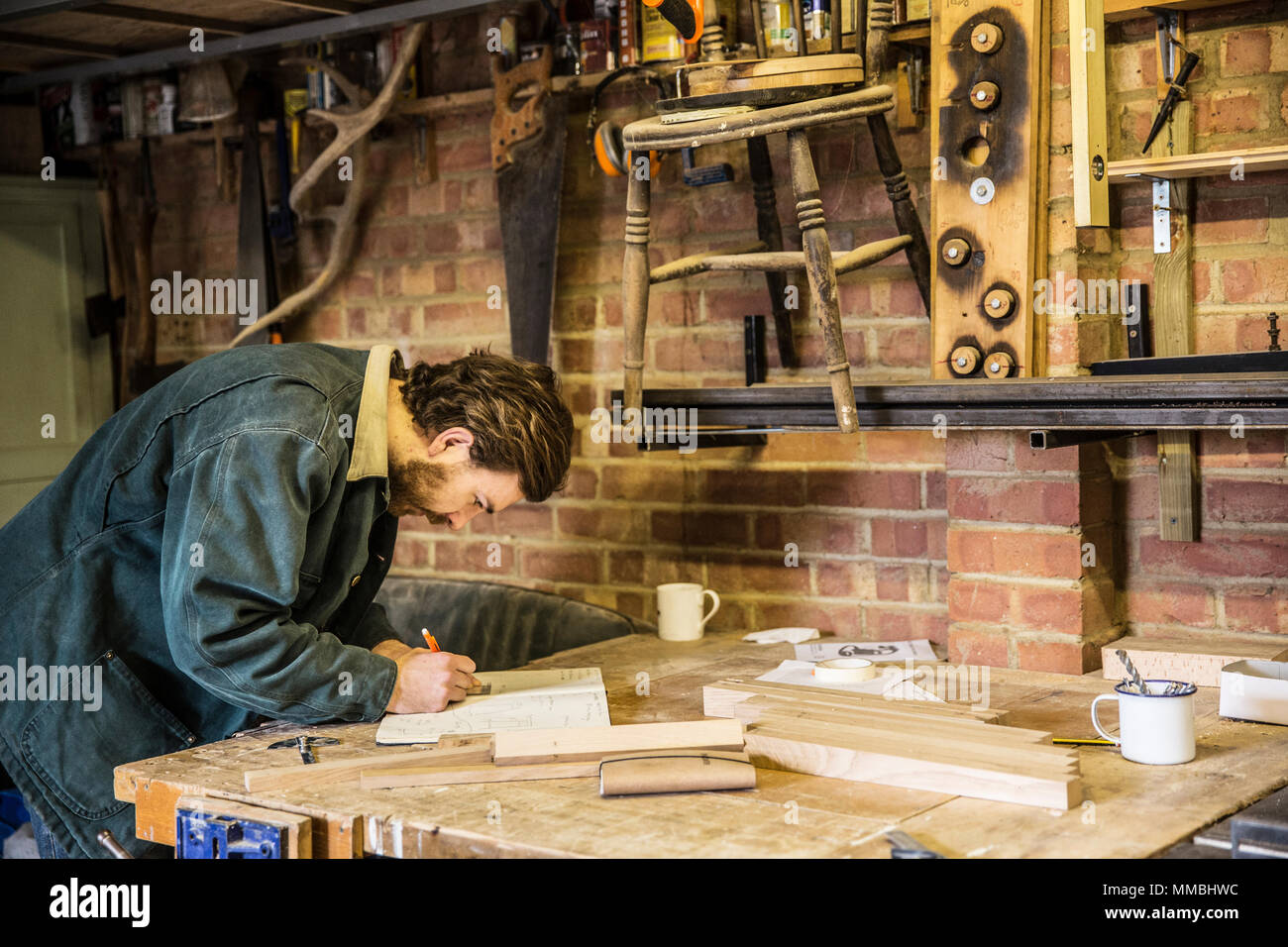 Man working standing at a workbench in a woodworking workshop, writing ...