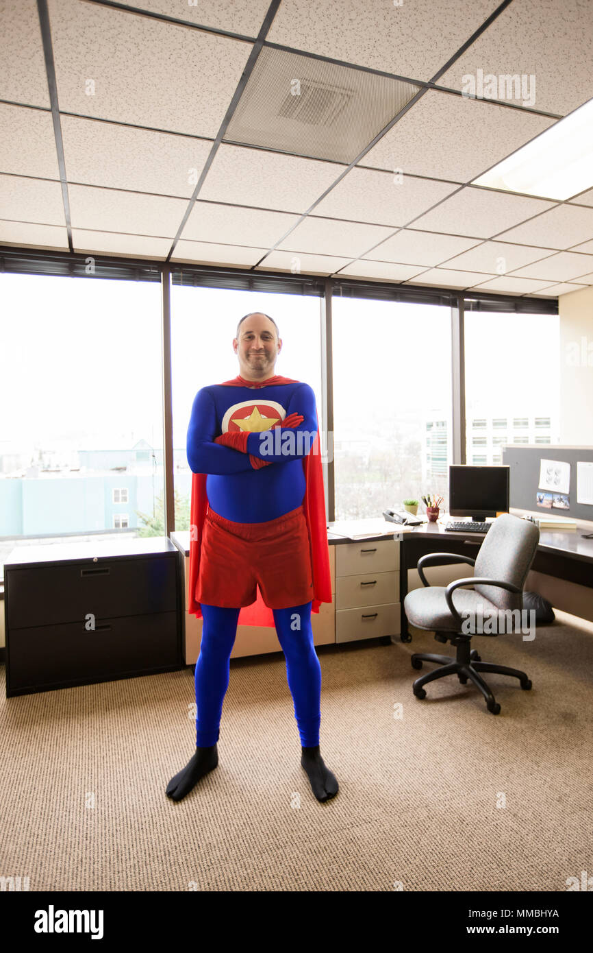 A self satisfied caucasian office super hero in his cubicle office ...