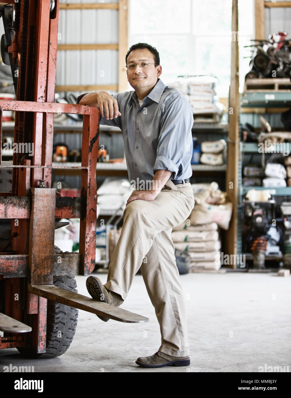 Hispanic man owner of a landscape company staning in the equipment room ...