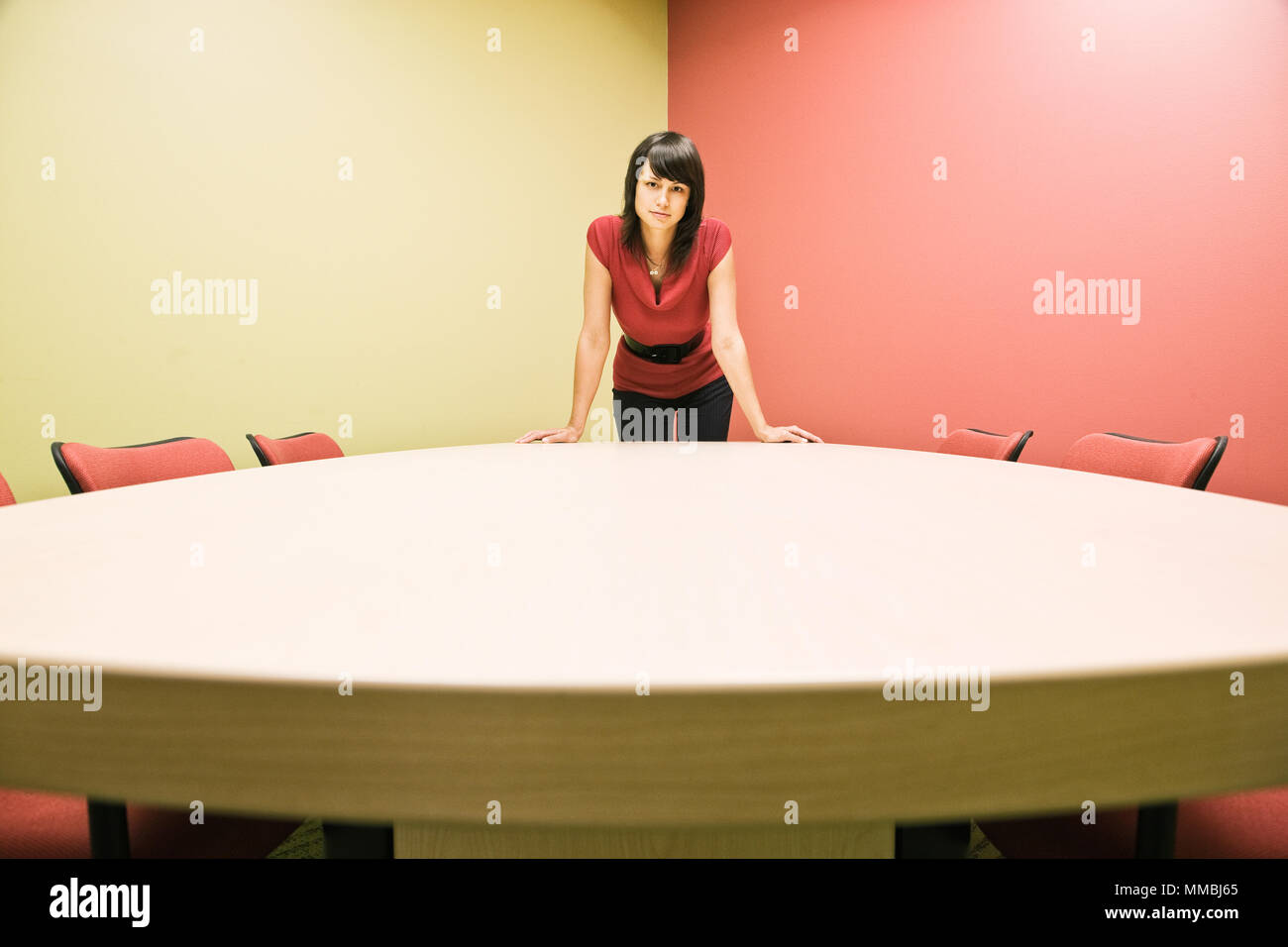 Caucasian woman in a conference room standing leaning on a table ...