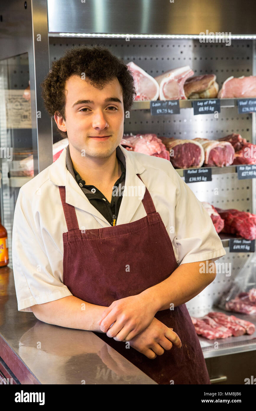 Man with brown curly hair wearing apron standing in butcher shop ...
