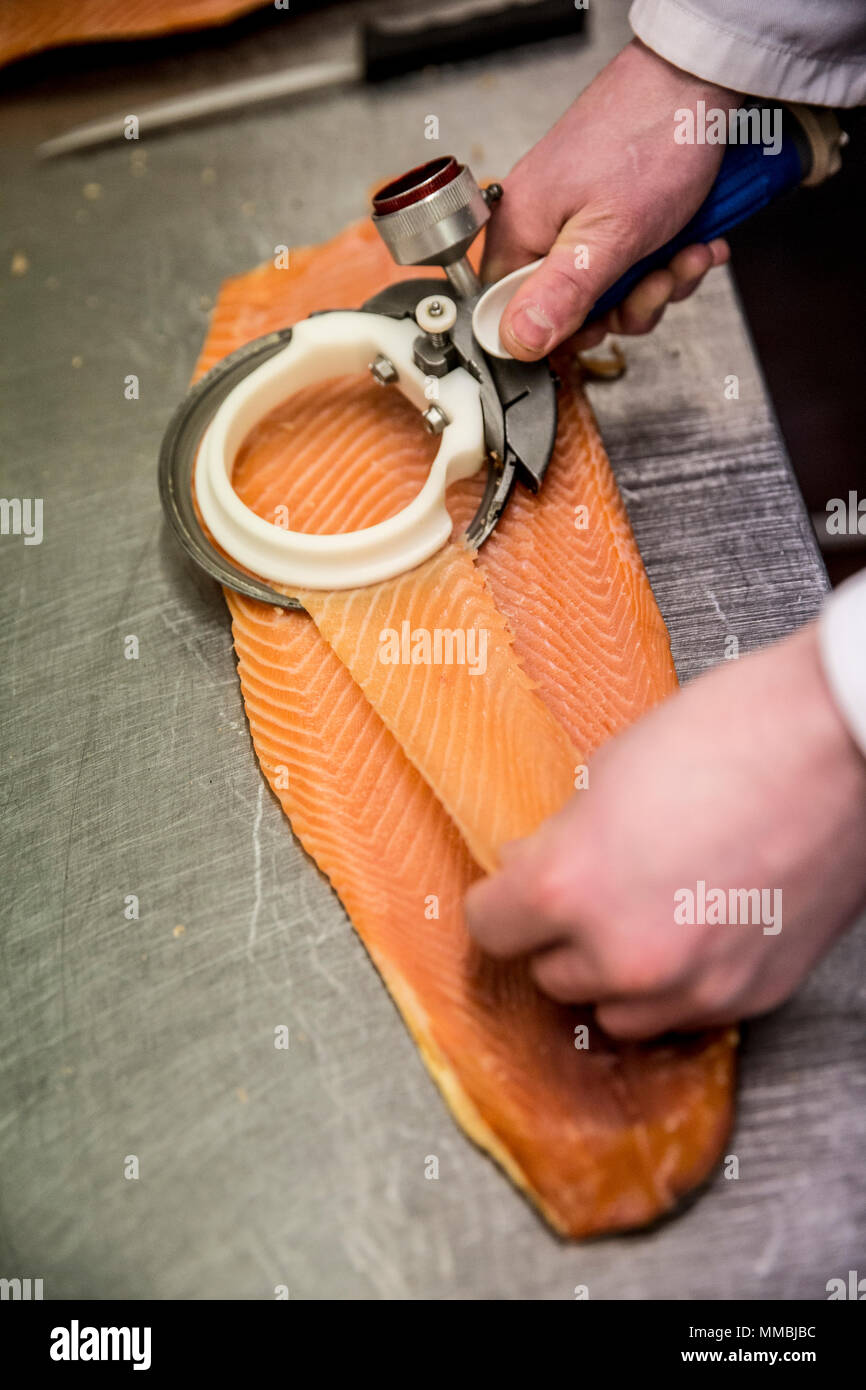High angle close up of fishmonger using special slicer to thinly slice ...
