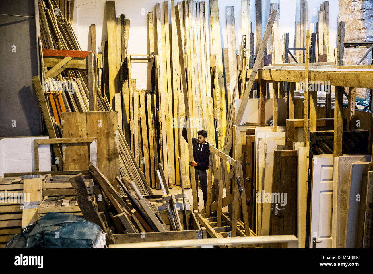 Interior view of warehouse with stacks of wooden planks, young man ...