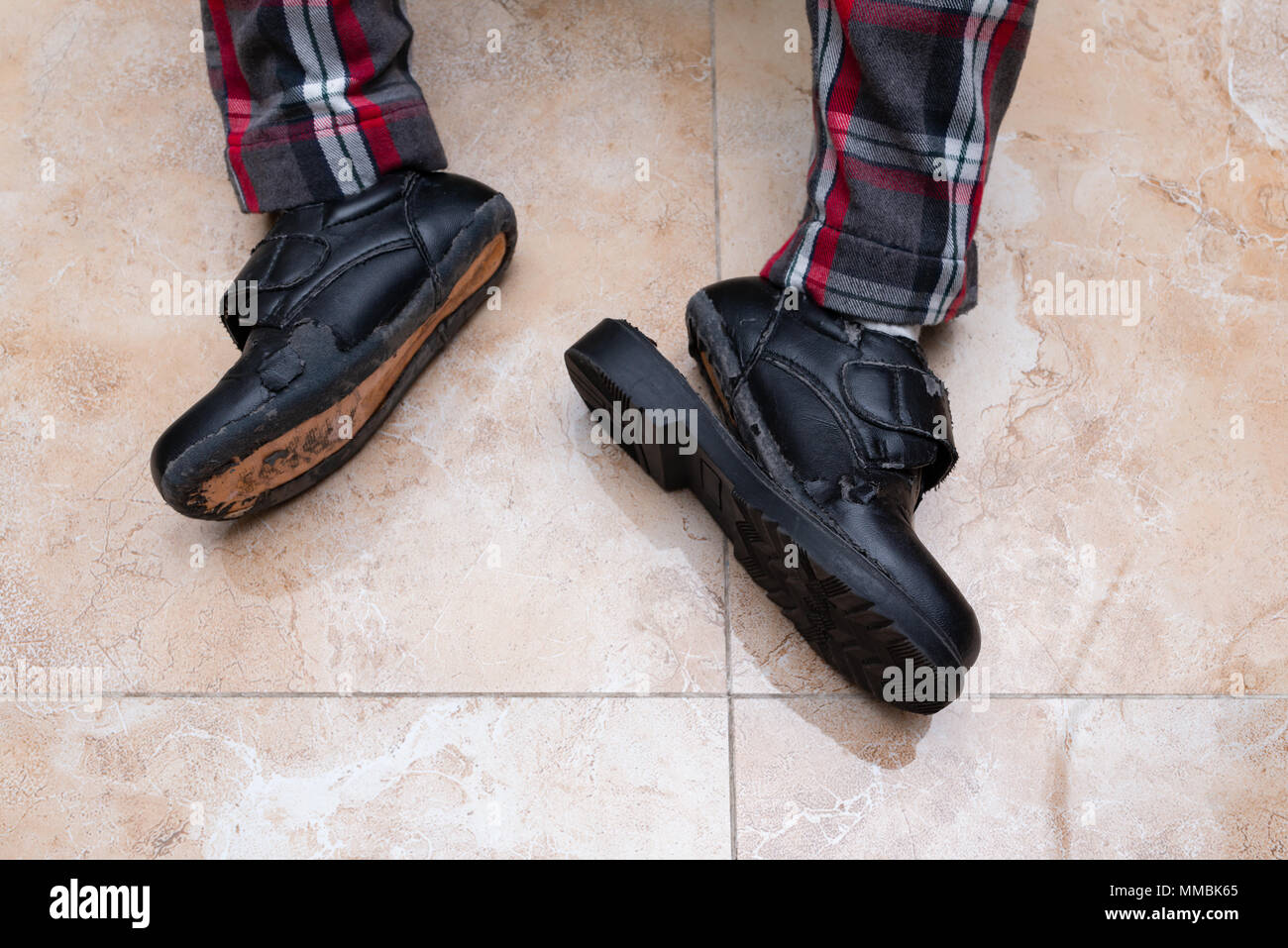 kid wearing a pair of badly worn out leather shoes Stock Photo - Alamy