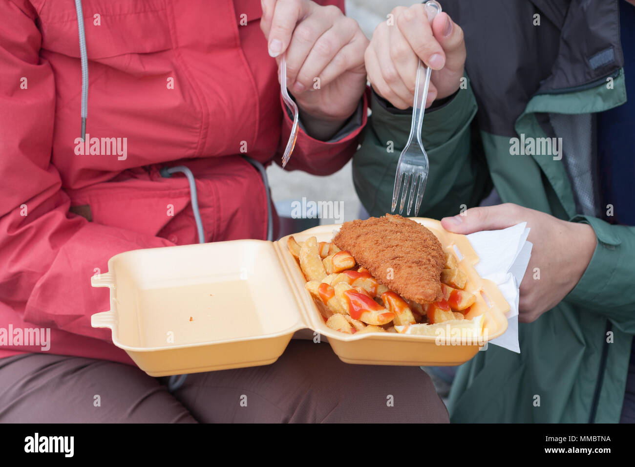 Young couple is eating traditional London food fish and chips from ...