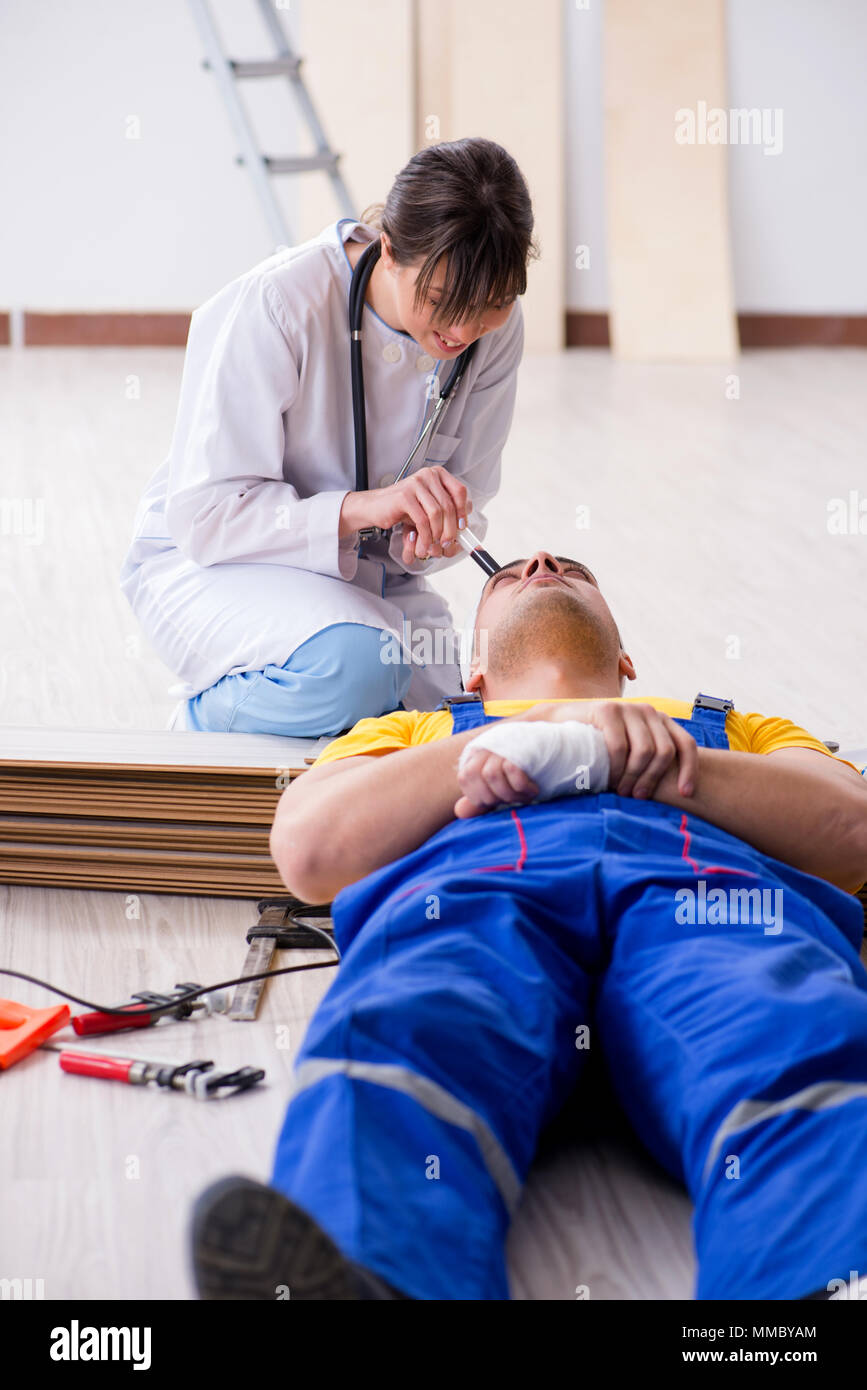 Doctor helping injured worker at construction site Stock Photo - Alamy