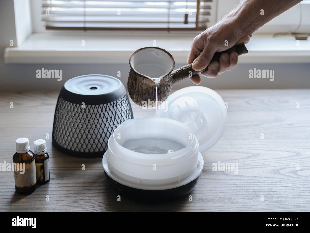 A man is pouring water into an aroma diffuser Stock Photo - Alamy