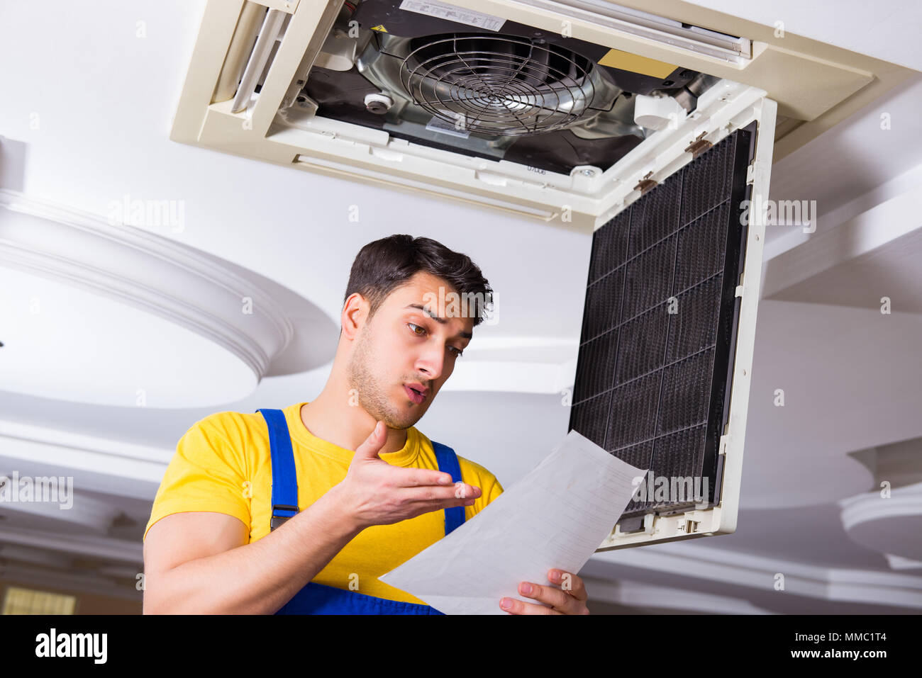 Repairman repairing ceiling air conditioning unit Stock Photo - Alamy