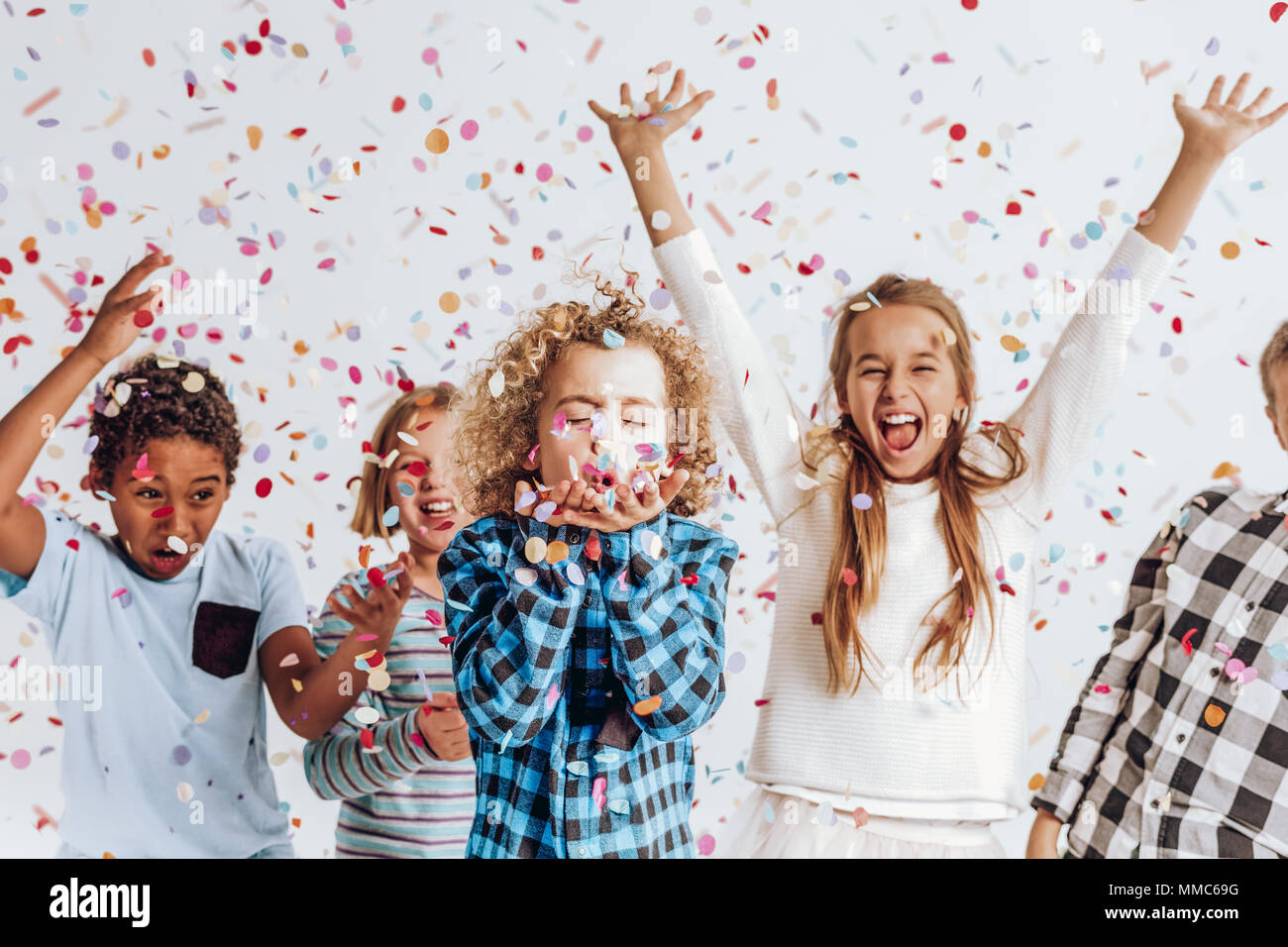 Happy kids having fun in a room full of confetti Stock Photo - Alamy