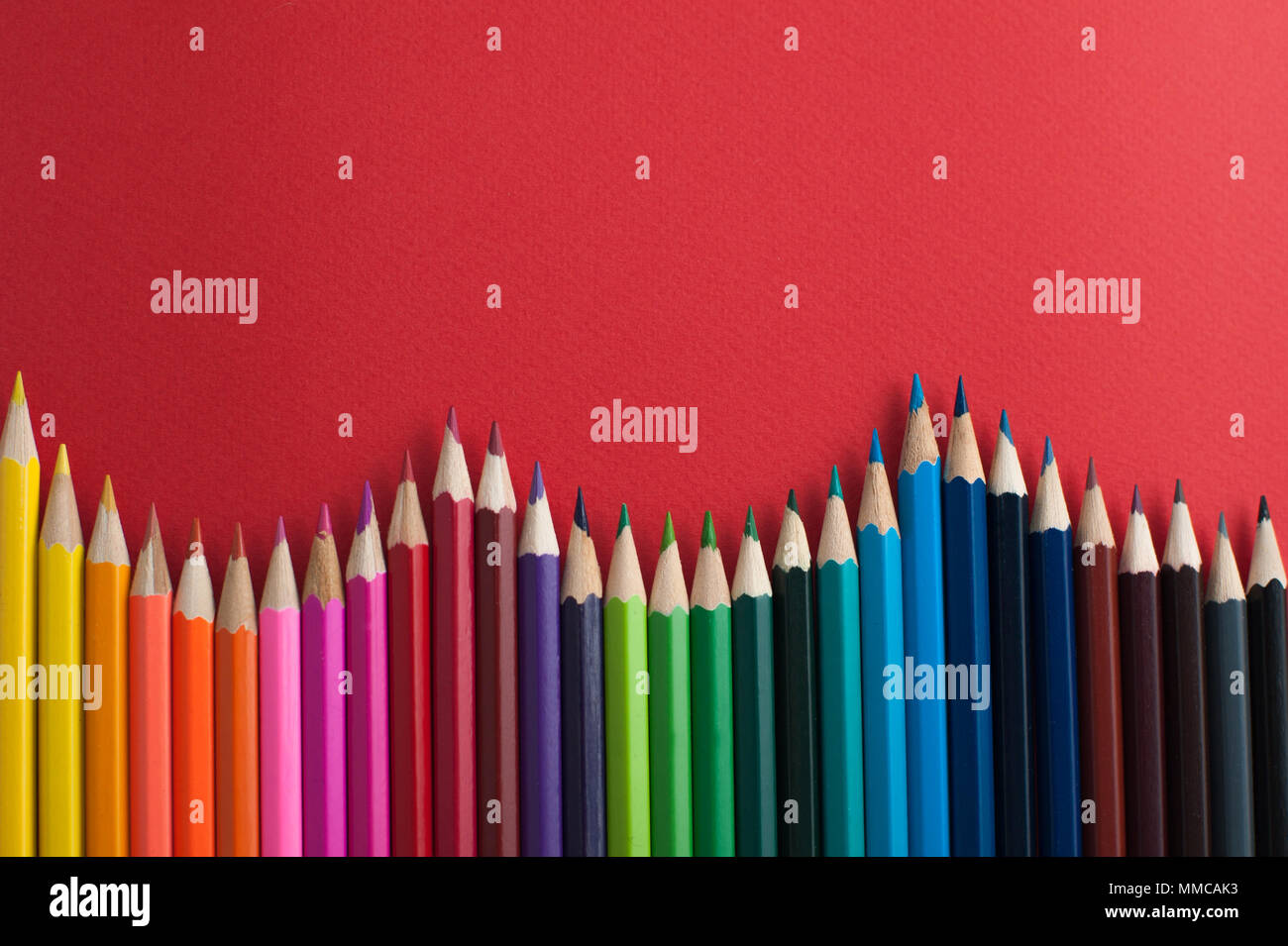 Colored pencils on a red background Stock Photo - Alamy