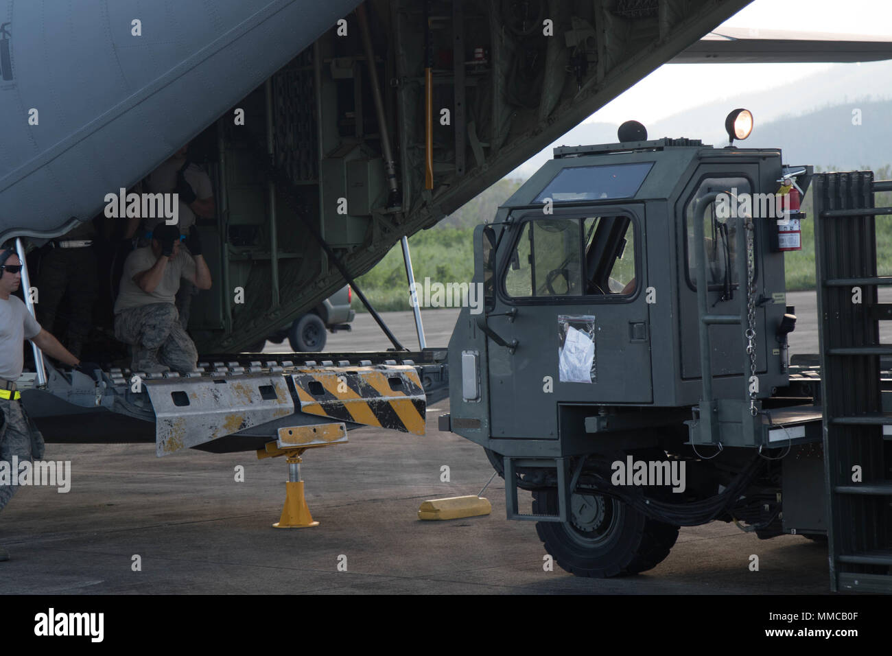 U.S. Air Force crew member guides a loaded floor truck in preparation ...