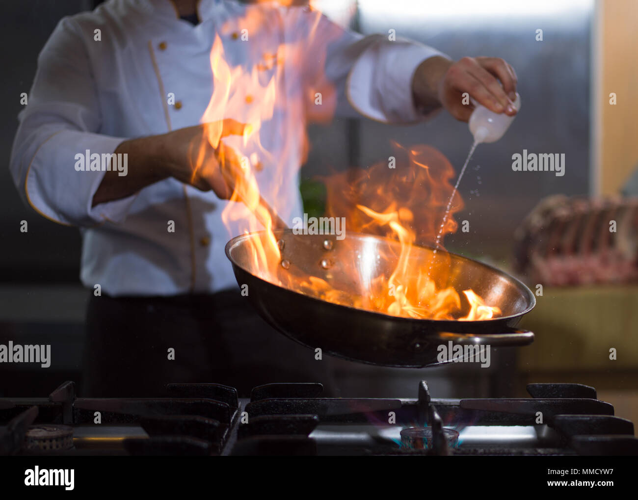 Chef cooking and doing flambe on food in restaurant kitchen Stock Photo ...