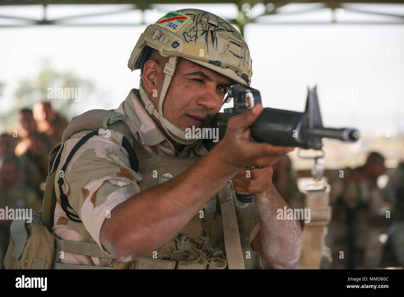 An Iraqi security forces member looks down the sights of an M16 rifle ...