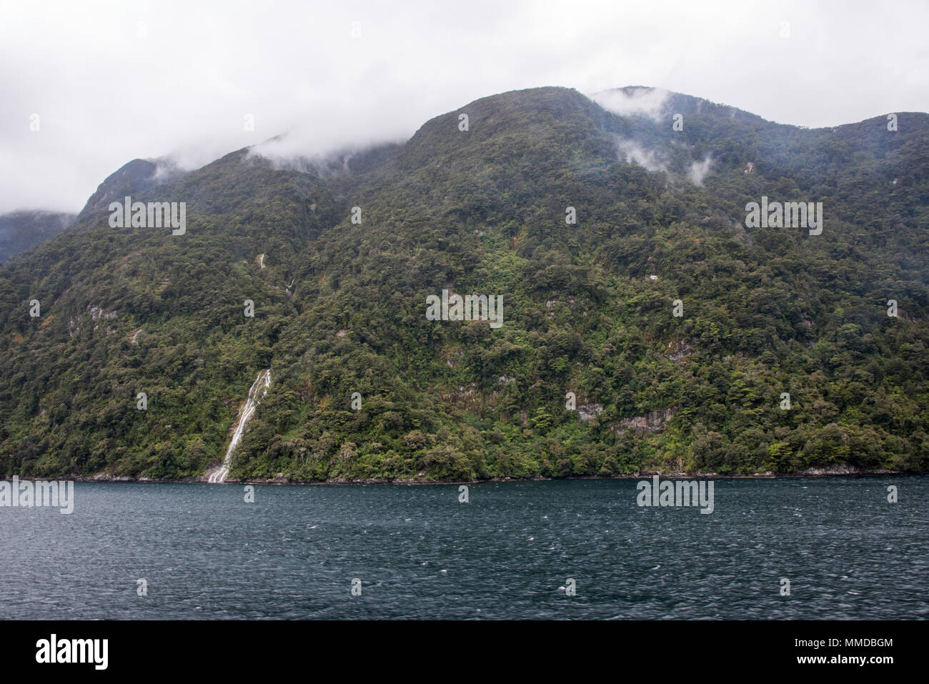 Waterfalls cascading in the lush mountain greenery in Fiordland ...