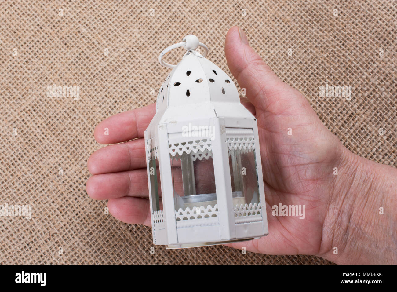 Old retro styled lantern in hand on canvas Stock Photo - Alamy