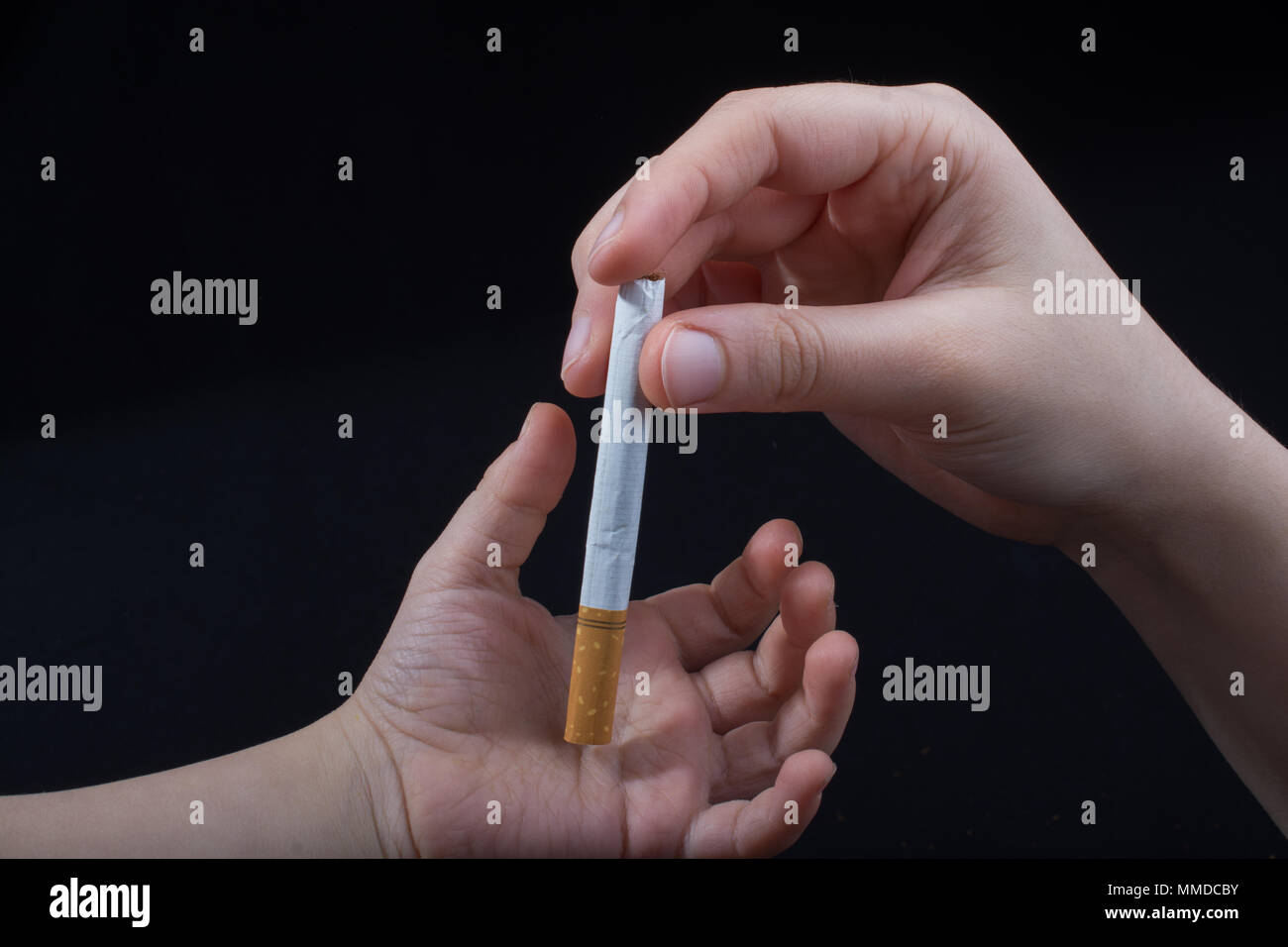 Hand is giving out cigarette on a black background Stock Photo - Alamy