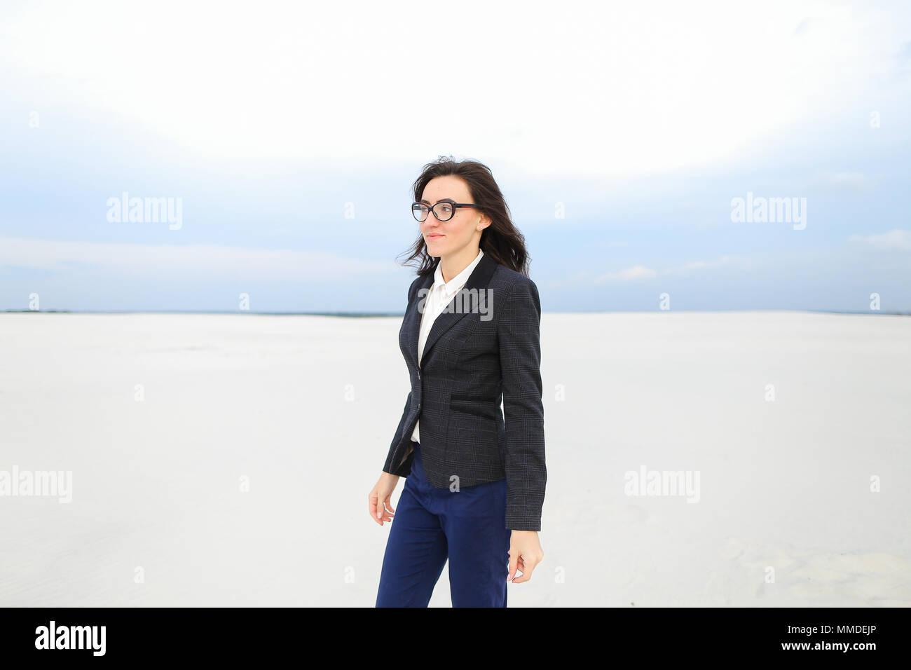 Female young secretary standing on snow and wearing jacket with glasses ...
