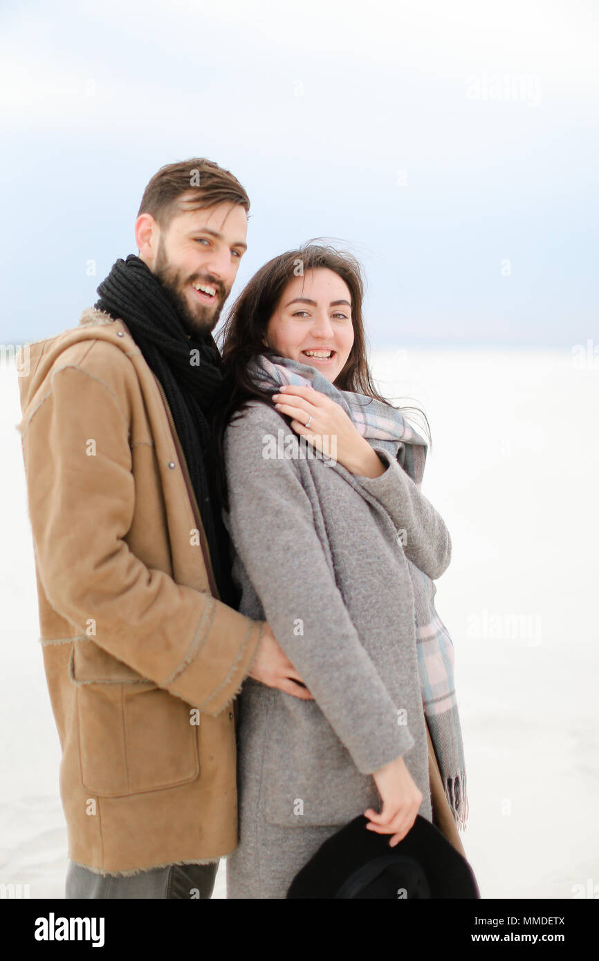 Happy smiling man hugging female person wearing grey coat and scarf ...