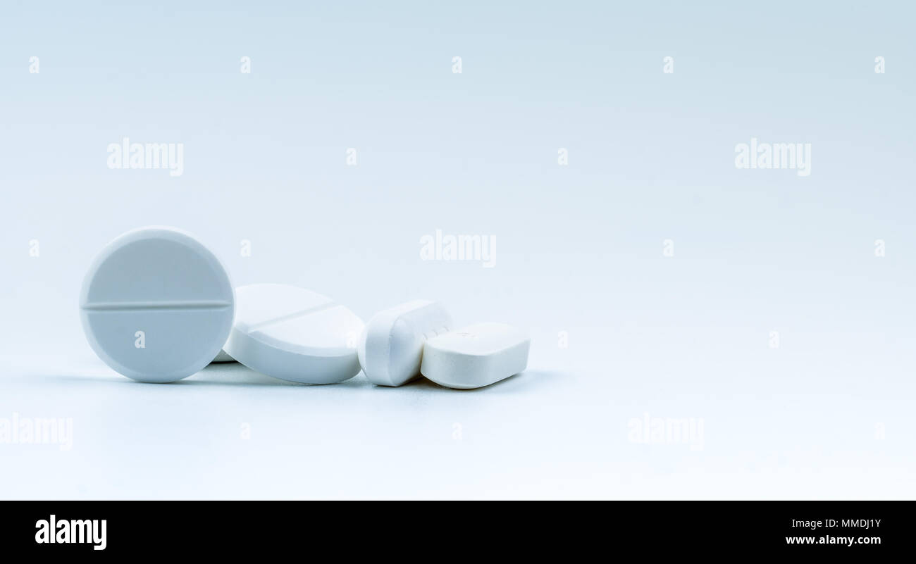 Pile of white round and oblong shape tablet pills isolated on white ...