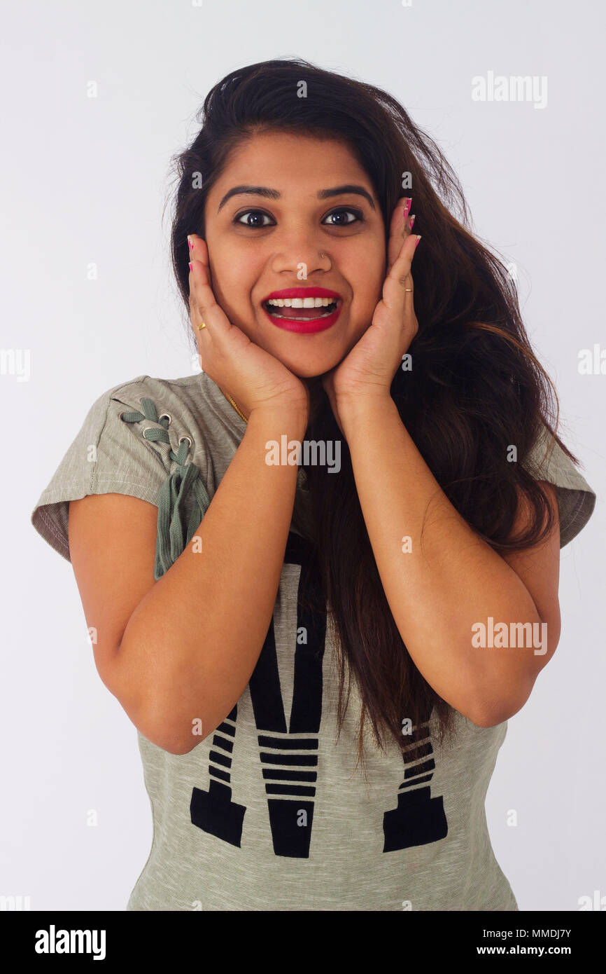 Stylish woman in grey top with both palms on face in a surprised look ...