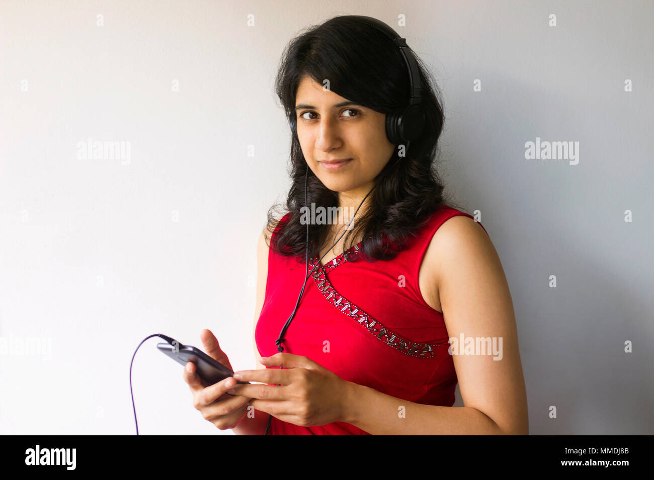 Stylish woman in red attire and mobile looking at camera. Front pose ...