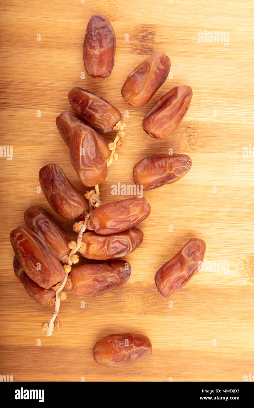 Branch of dried dates on a wooden background, fruits of date palm with ...
