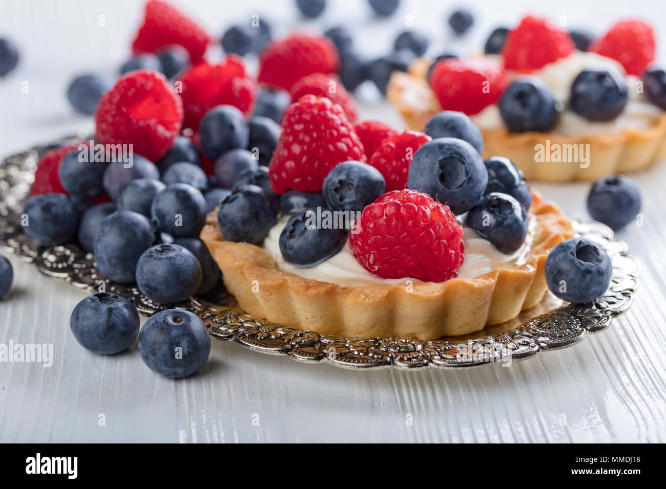 Dessert tarts with raspberries and blueberries on a wooden table ...