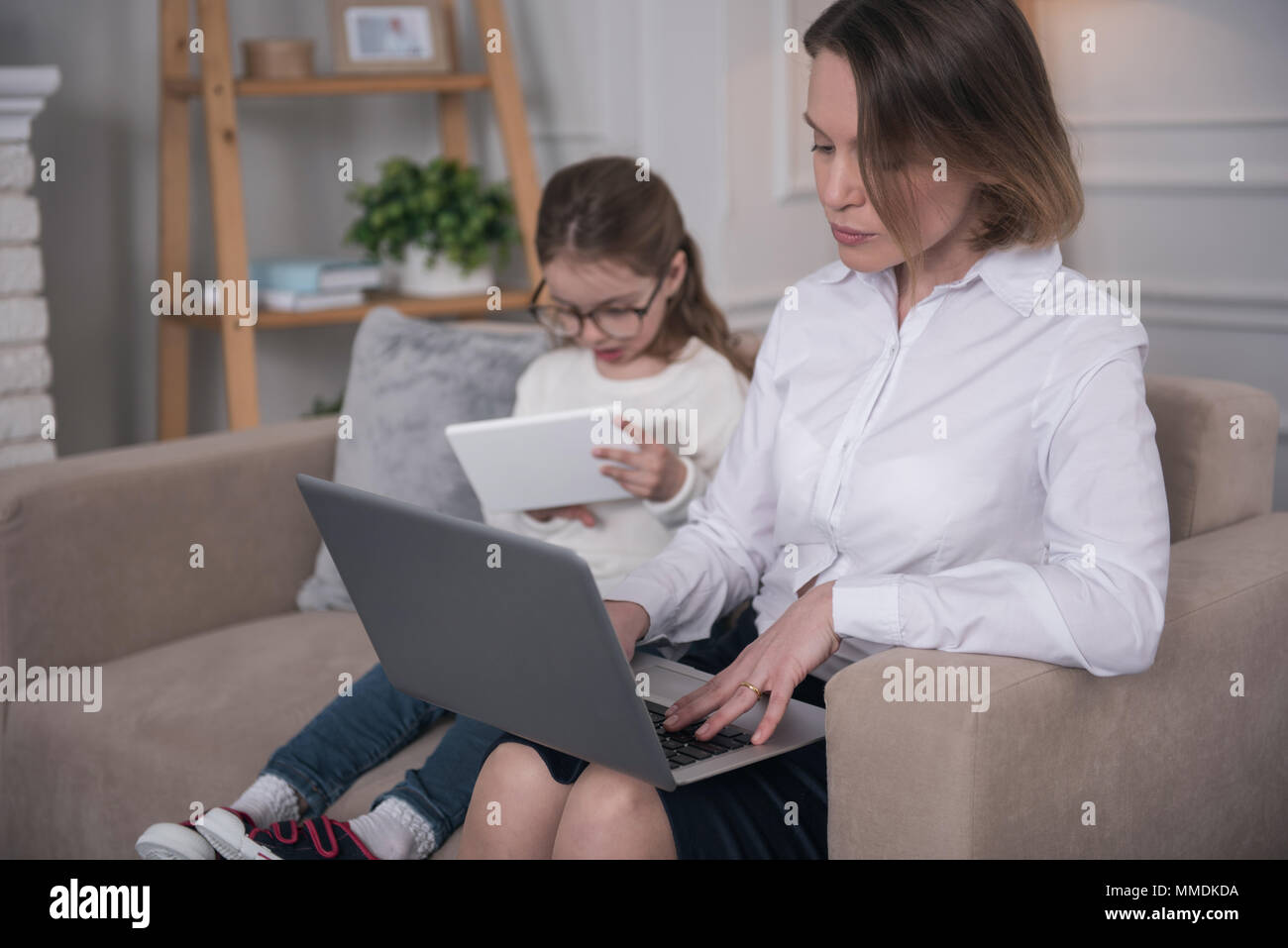 Concentrated mother working on her laptop Stock Photo - Alamy