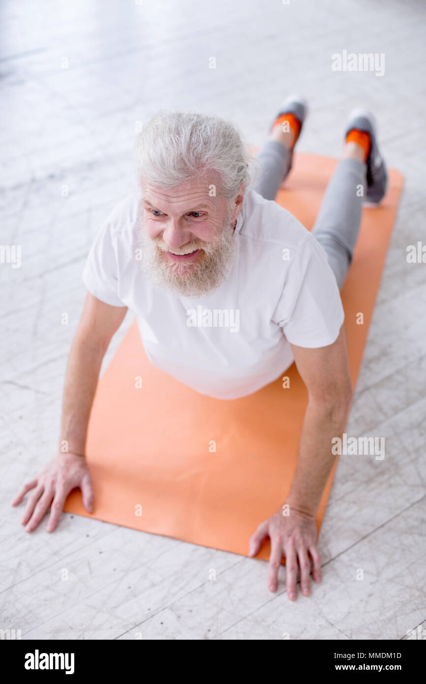 Upbeat elderly man standing in upward-facing dog pose Stock Photo - Alamy