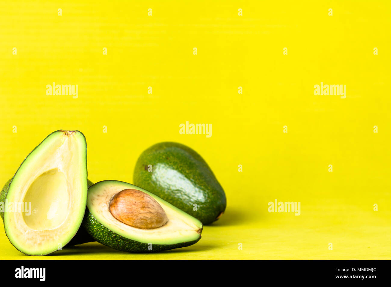 Avocado halves and group of Avocados on yellow pastel background, food ...