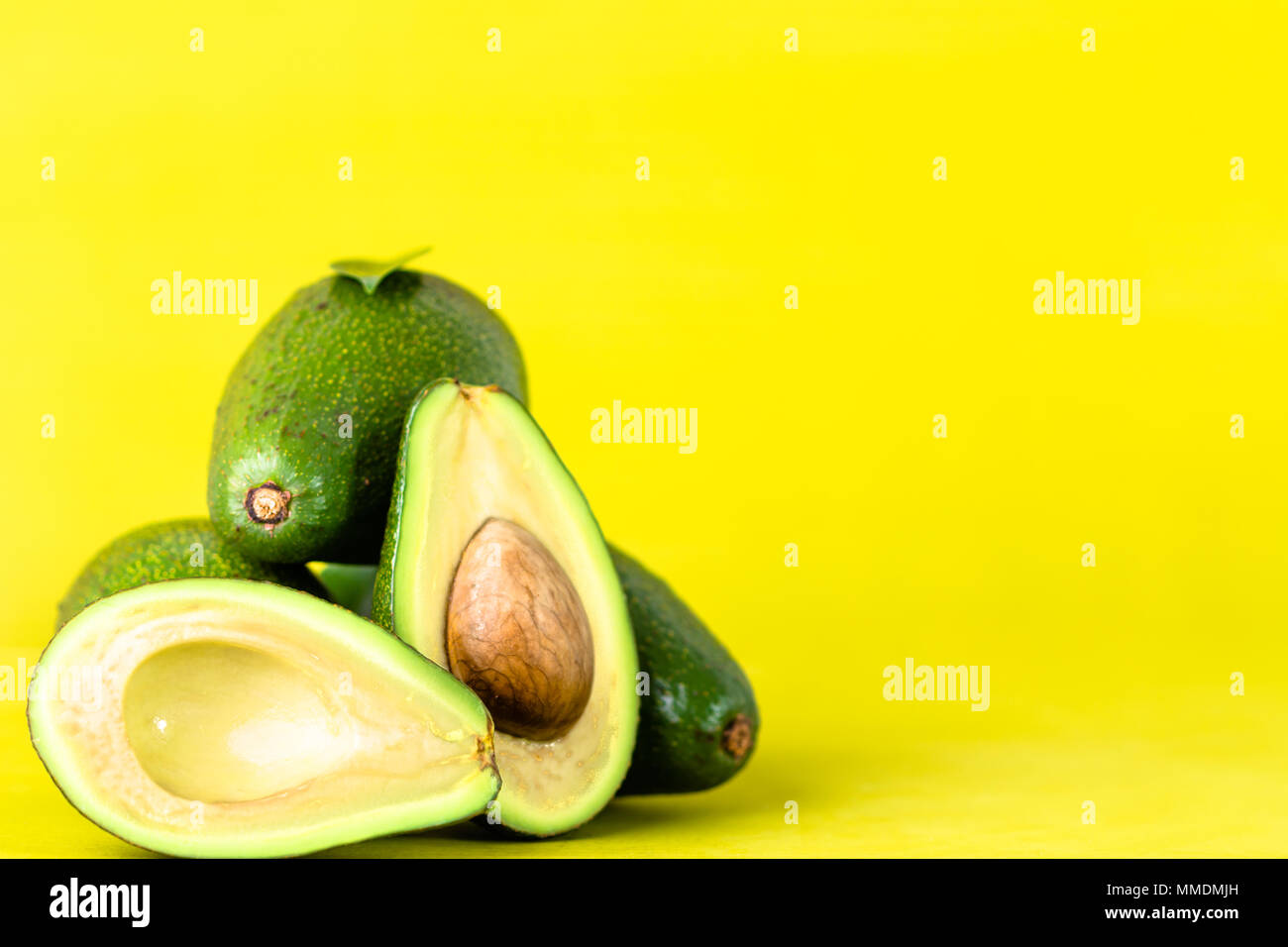 Avocado halves and group of Avocados on yellow pastel background, food ...