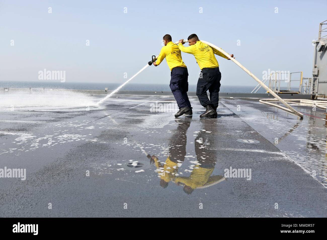 Sailors pressure wash the flight deck in preparation for night ...