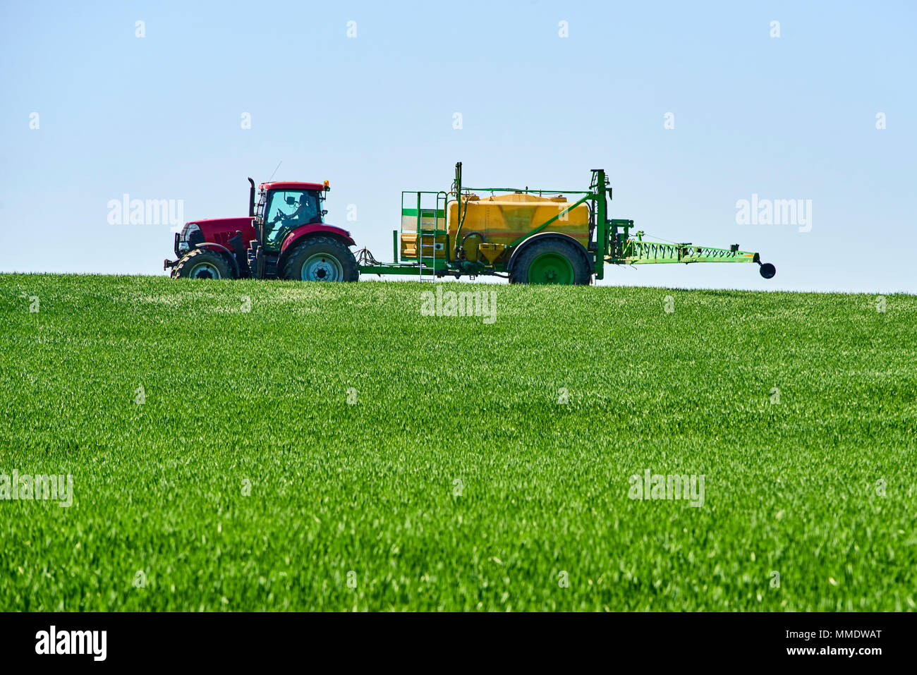 Tractor spraying wheat field with sprayer Stock Photo - Alamy