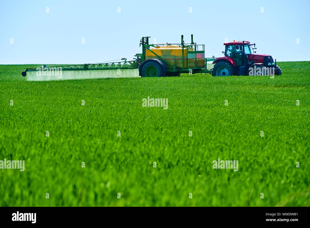 Tractor spraying wheat field with sprayer Stock Photo - Alamy