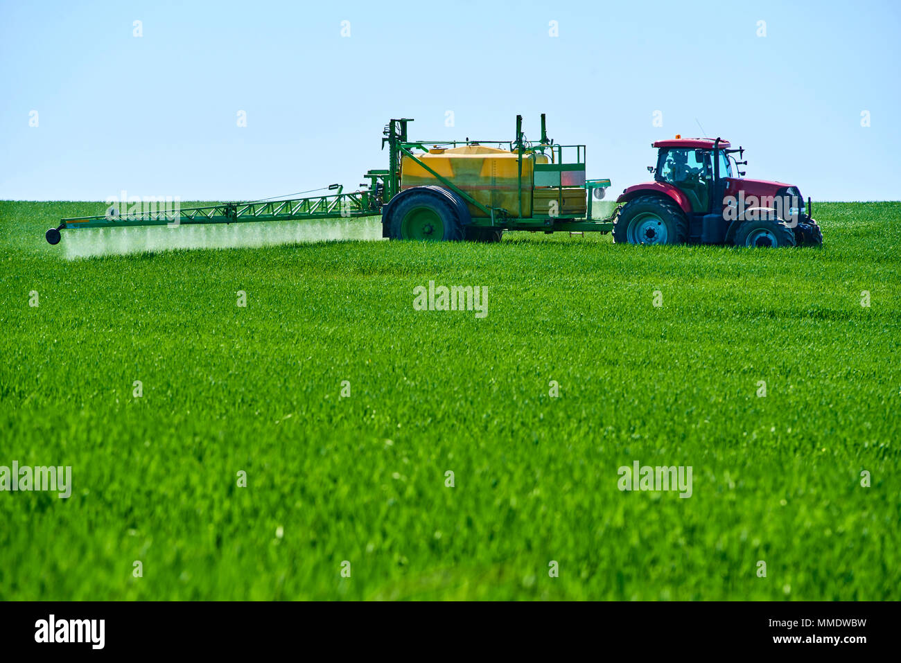 Tractor spraying wheat field with sprayer Stock Photo - Alamy