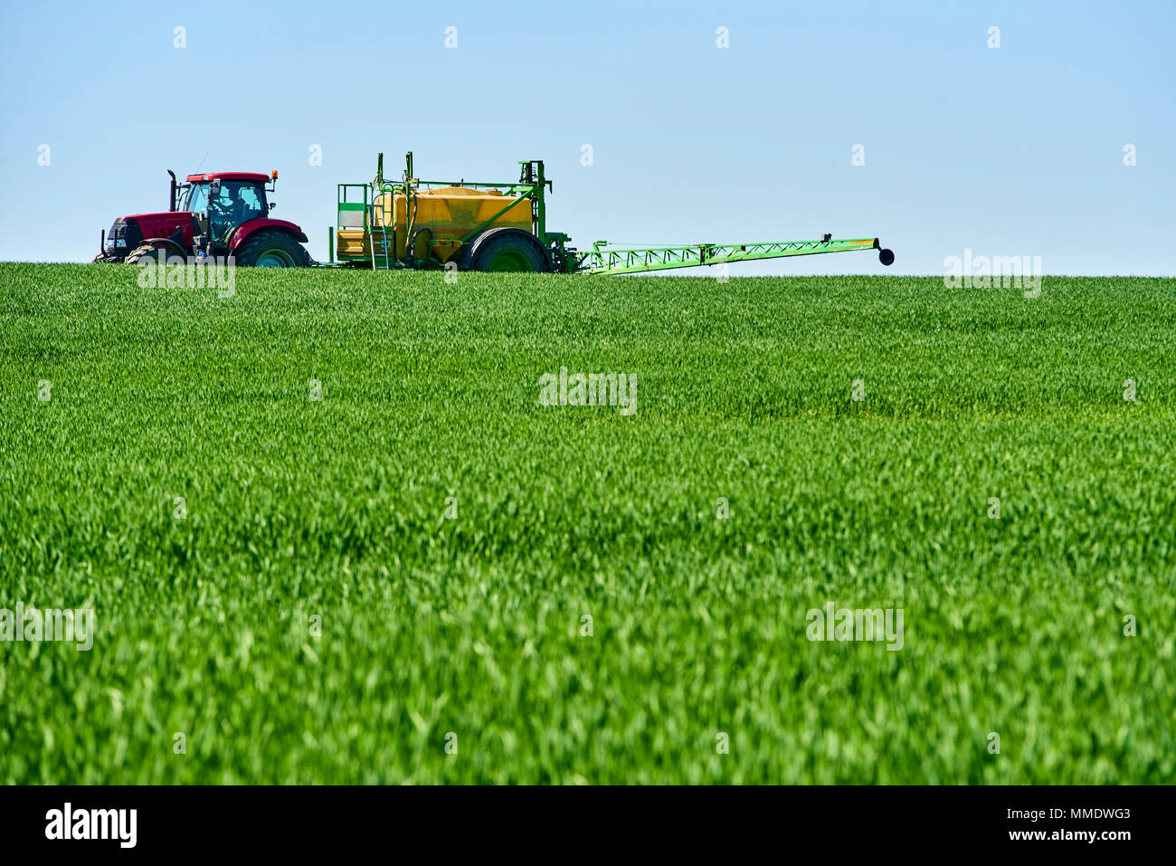 Tractor spraying wheat field with sprayer Stock Photo - Alamy