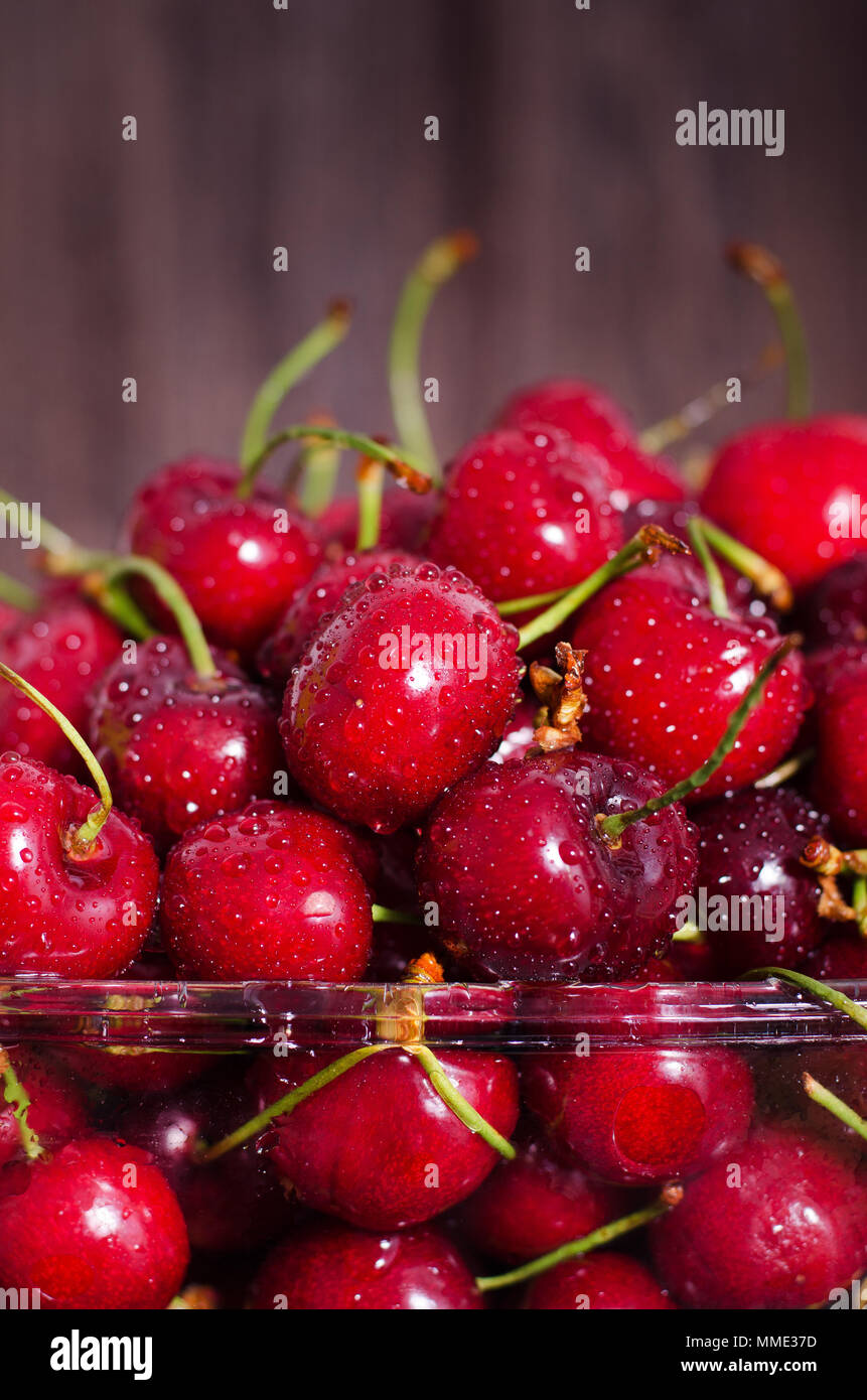 Sweet red cherries in glass bowl on dark wooden backgound with copy ...