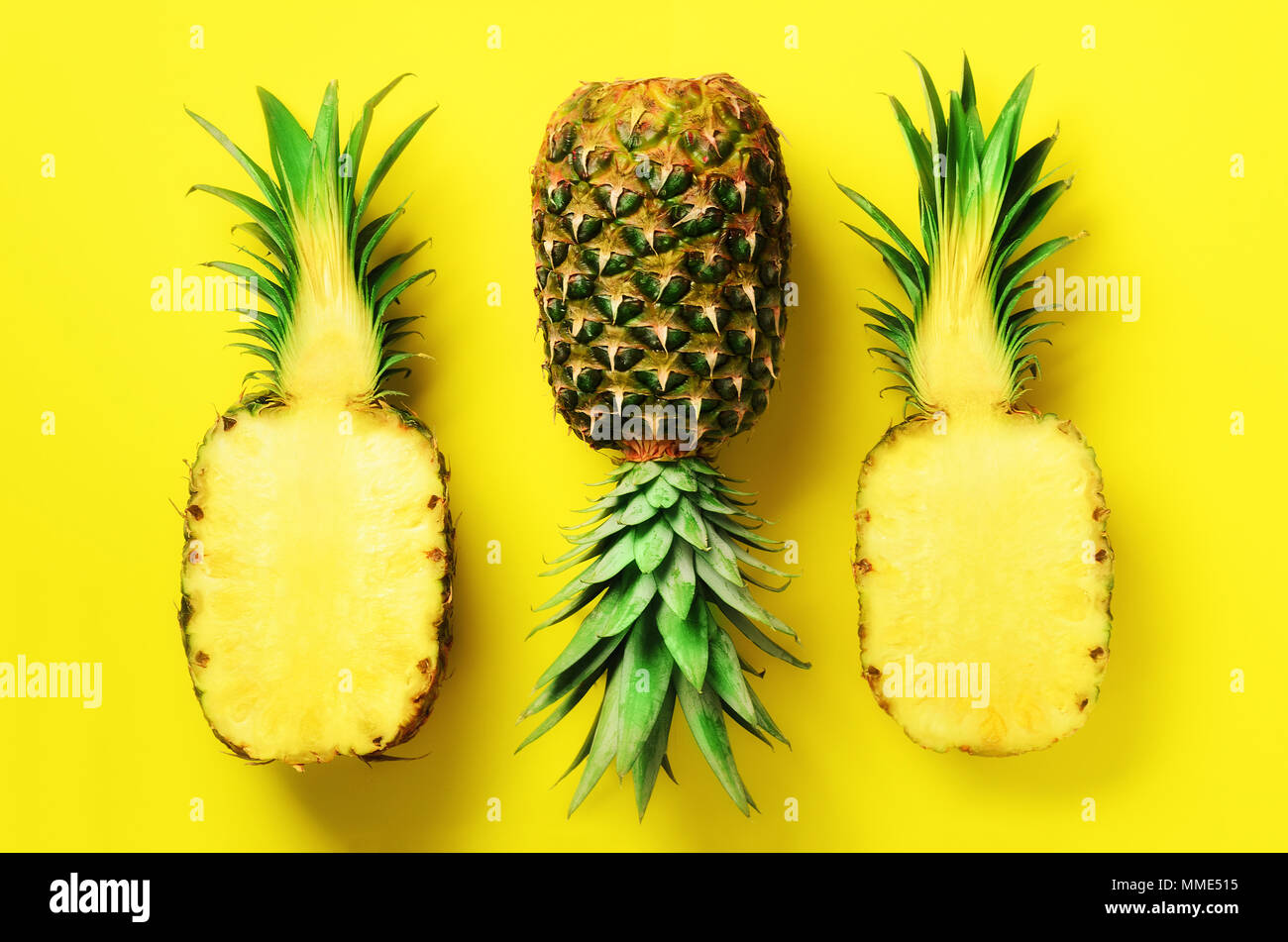 Half slice of fresh pineapple and whole fruit on yellow background. Top ...
