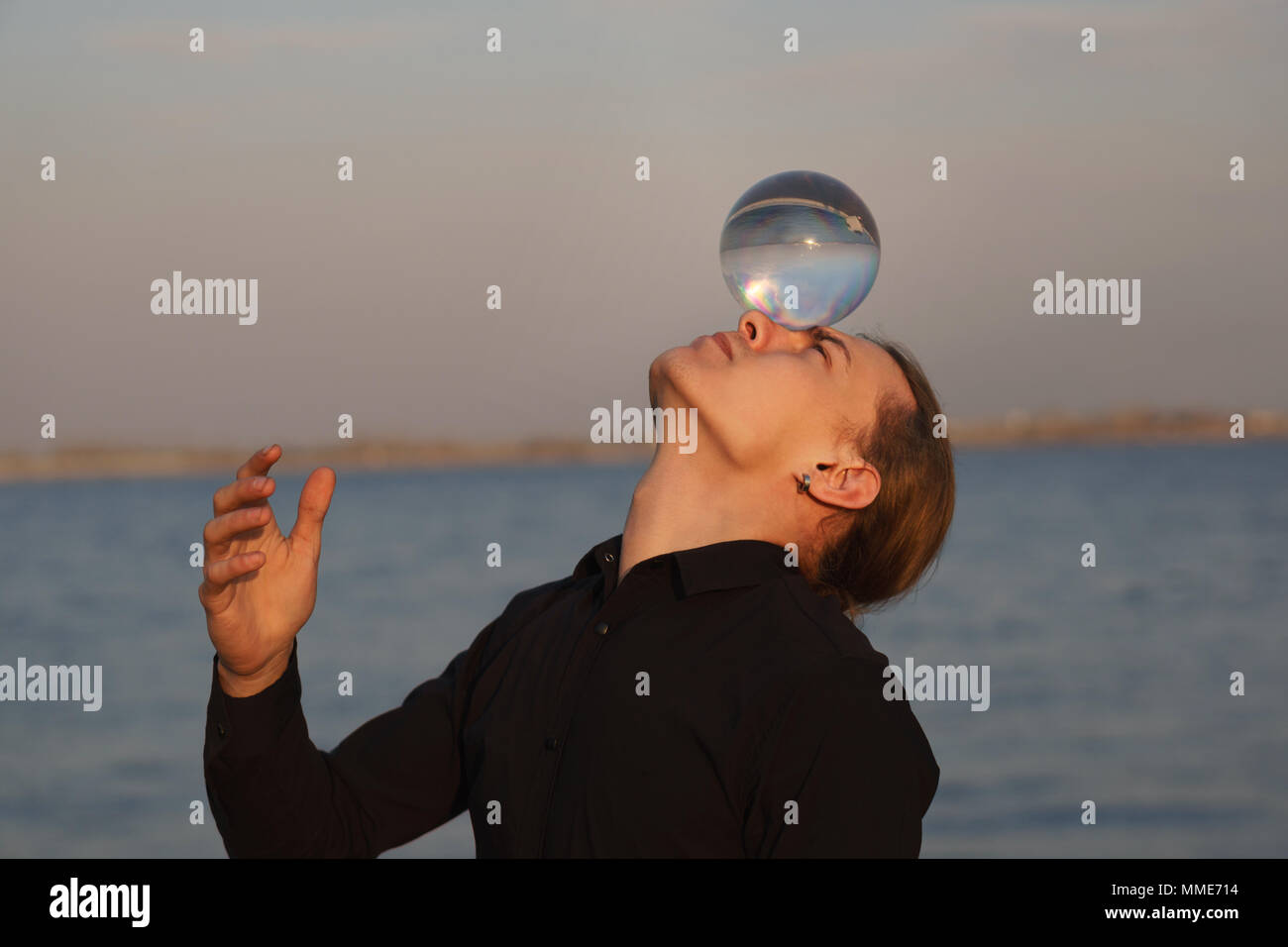 Contact juggling. Guy balances with glass ball on his head. Reflection ...