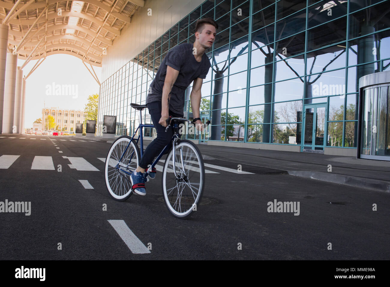 young man riding on bicycle in city street. Man on blue bicycle with ...