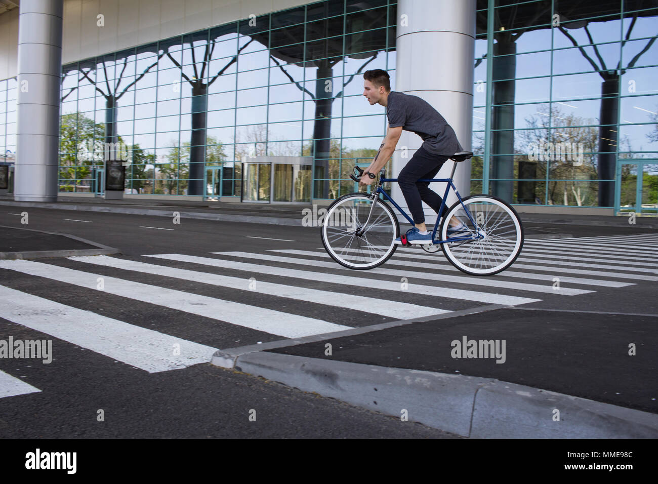 young man riding on bicycle in city street. Man on blue bicycle with ...