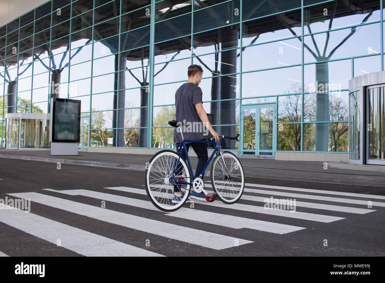 The guy in grey shirt on shop window background. a young man near blue ...