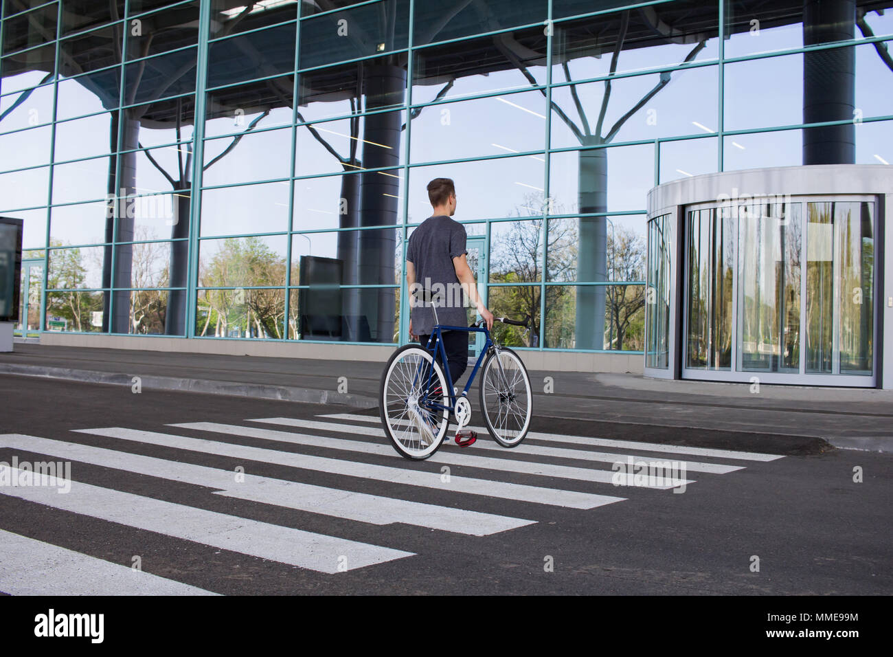 The guy in grey shirt on shop window background. a young man near blue ...