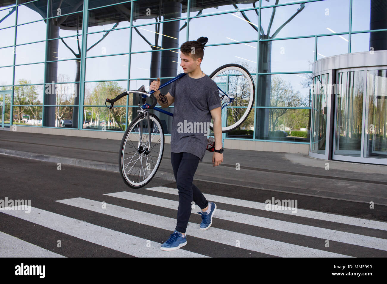 The guy in grey shirt on shop window background. a young man near blue ...