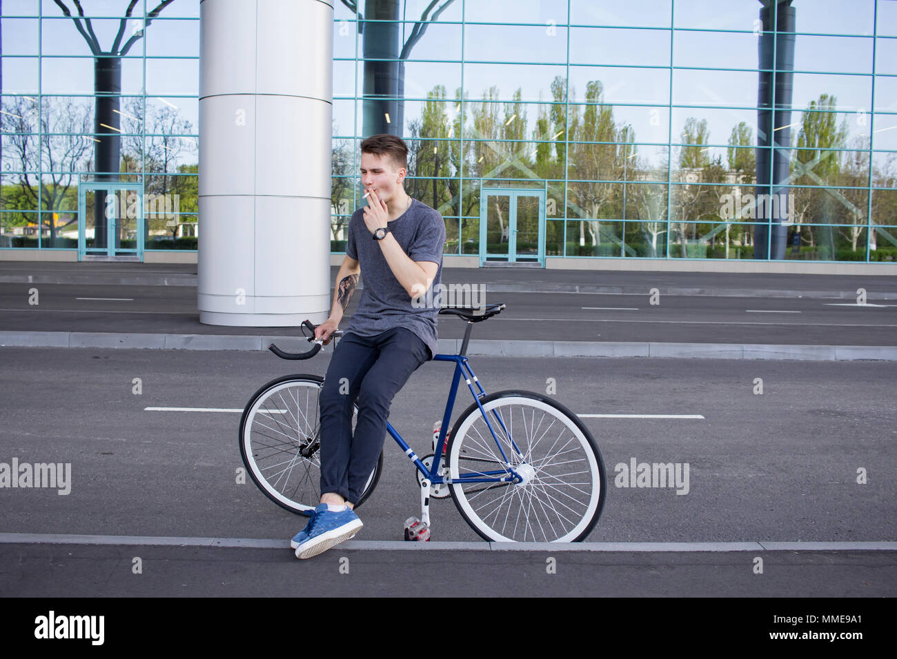 The guy in grey shirt on shop window background. a young man near blue ...