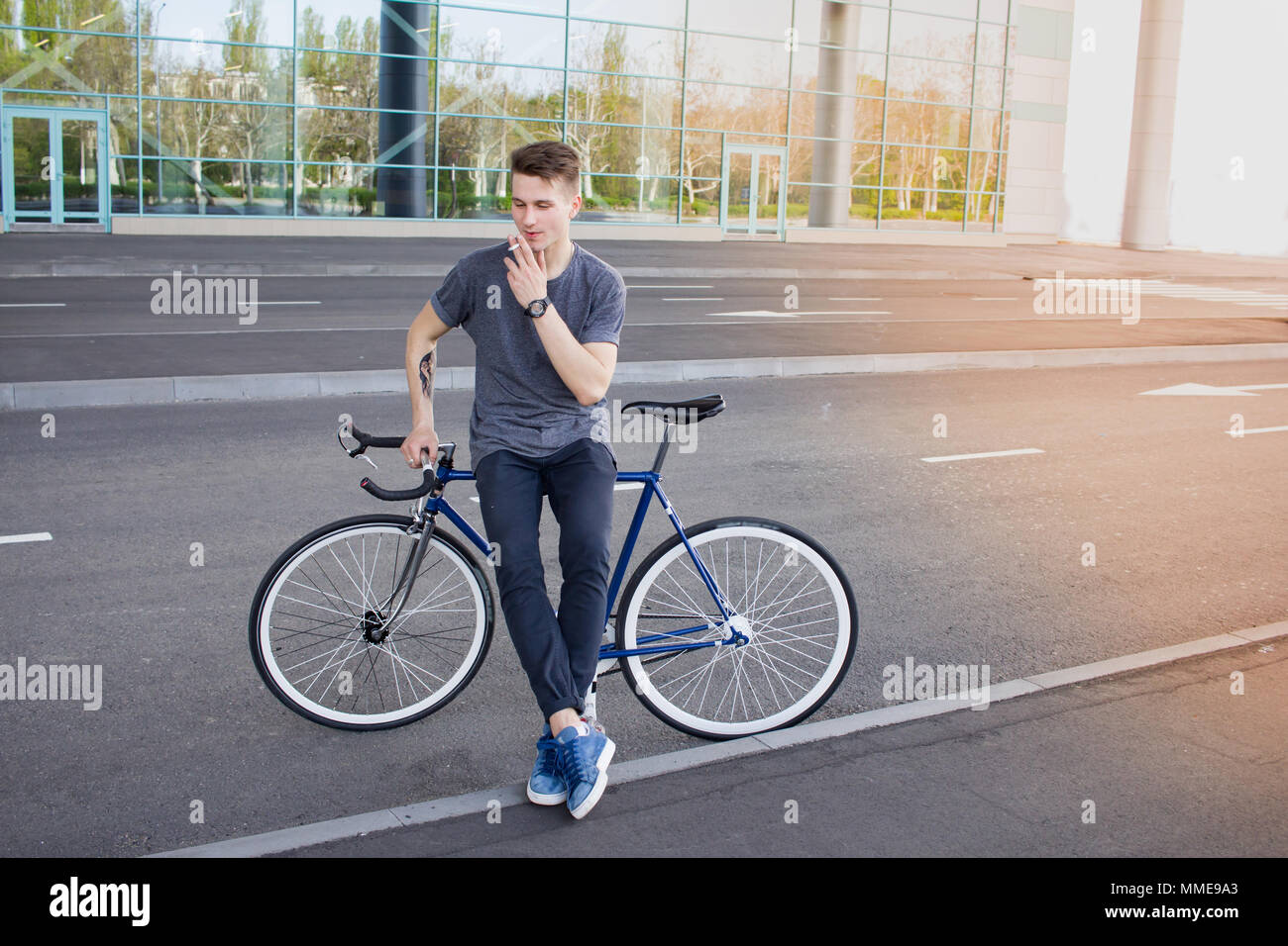 The guy in grey shirt on shop window background. a young man near blue ...