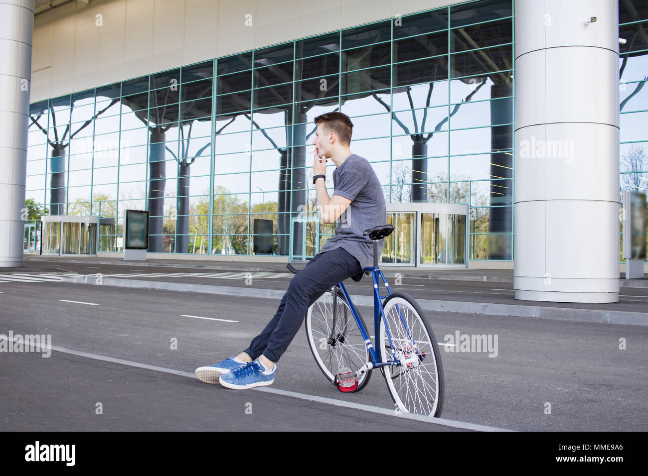 The guy in grey shirt on shop window background. a young man near blue ...