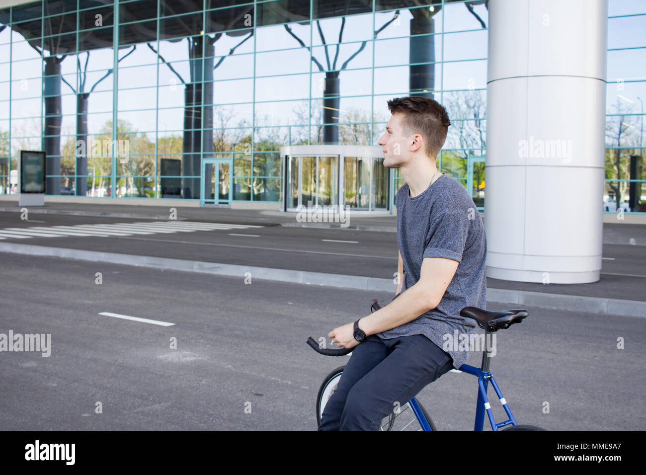 The guy in grey shirt on shop window background. a young man near blue ...